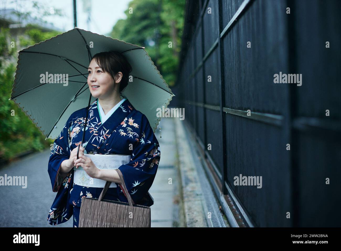 Woman walking alone in the rain with bag asian hi-res stock photography ...