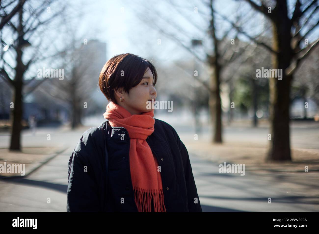 A woman wearing a scarf and jacket standing in the middle of a street ...