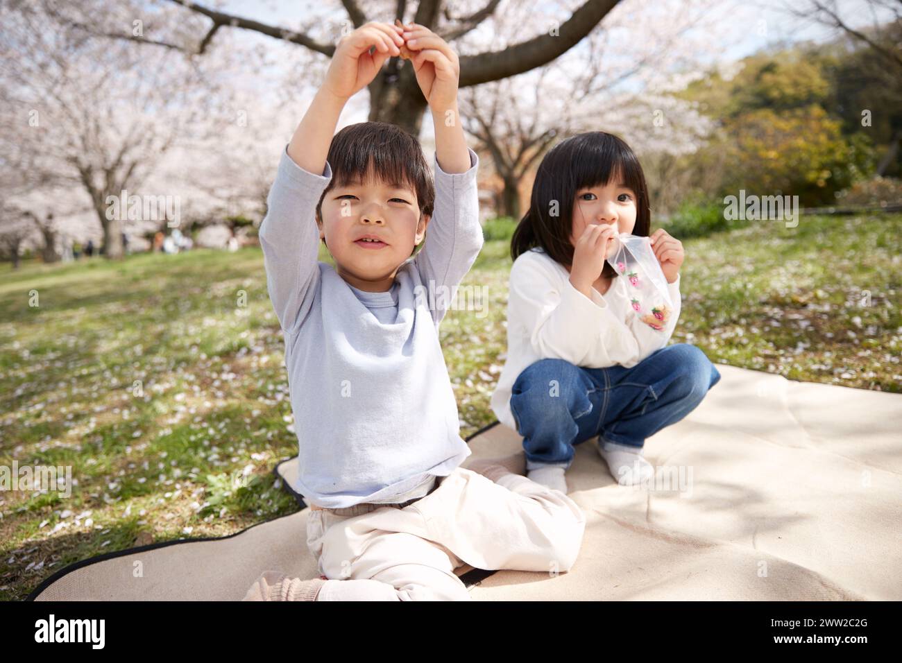 Two children sitting on a blanket Stock Photo - Alamy