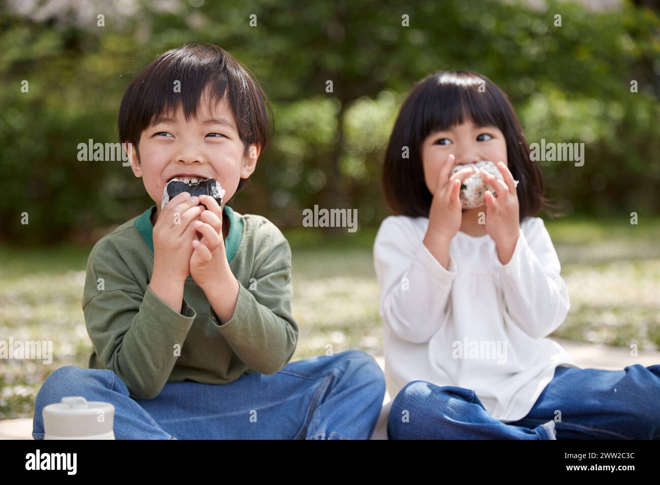 Two children sitting on the ground eating Stock Photo - Alamy