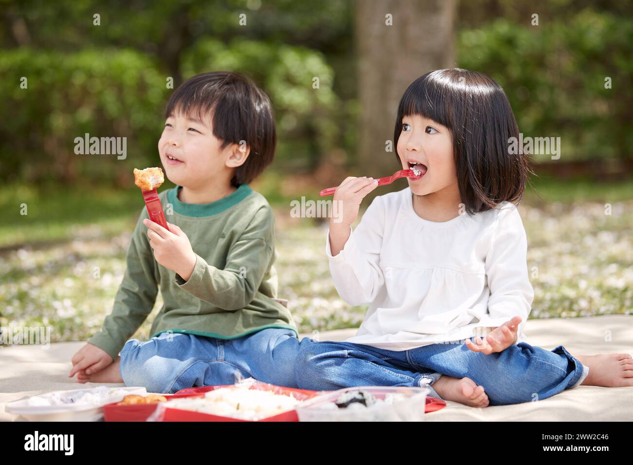 Two children sitting on the ground eating food Stock Photo - Alamy