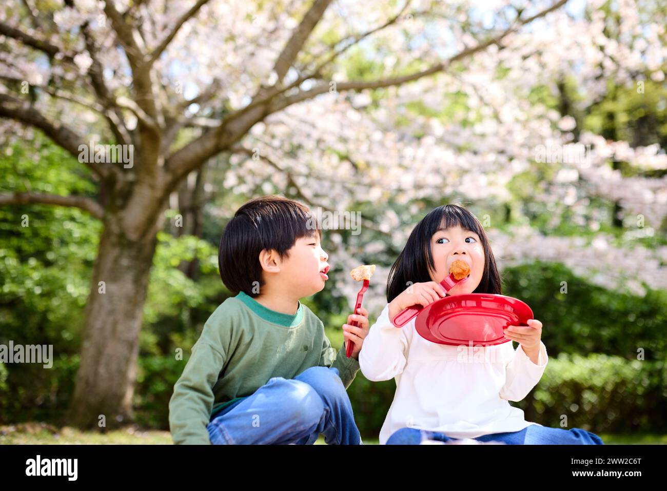 Two children eating food in the park Stock Photo - Alamy