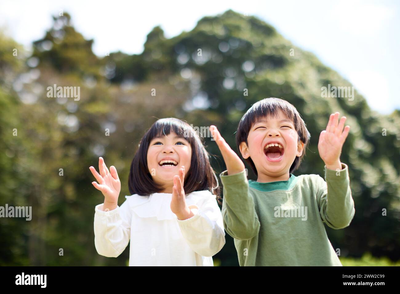 Two children laughing and waving in the air Stock Photo - Alamy