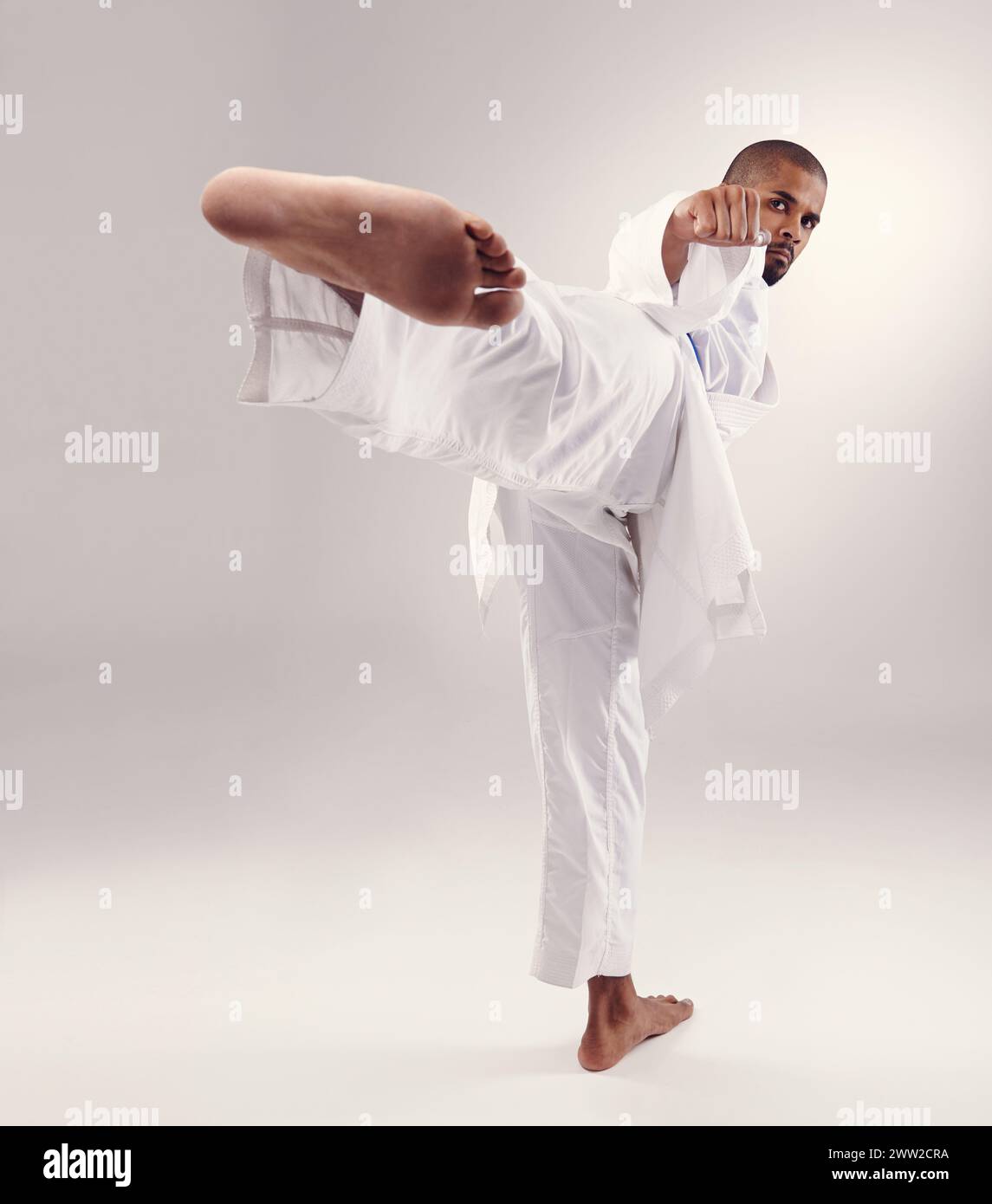 Karate, exercise and man kick in portrait on studio, white background ...
