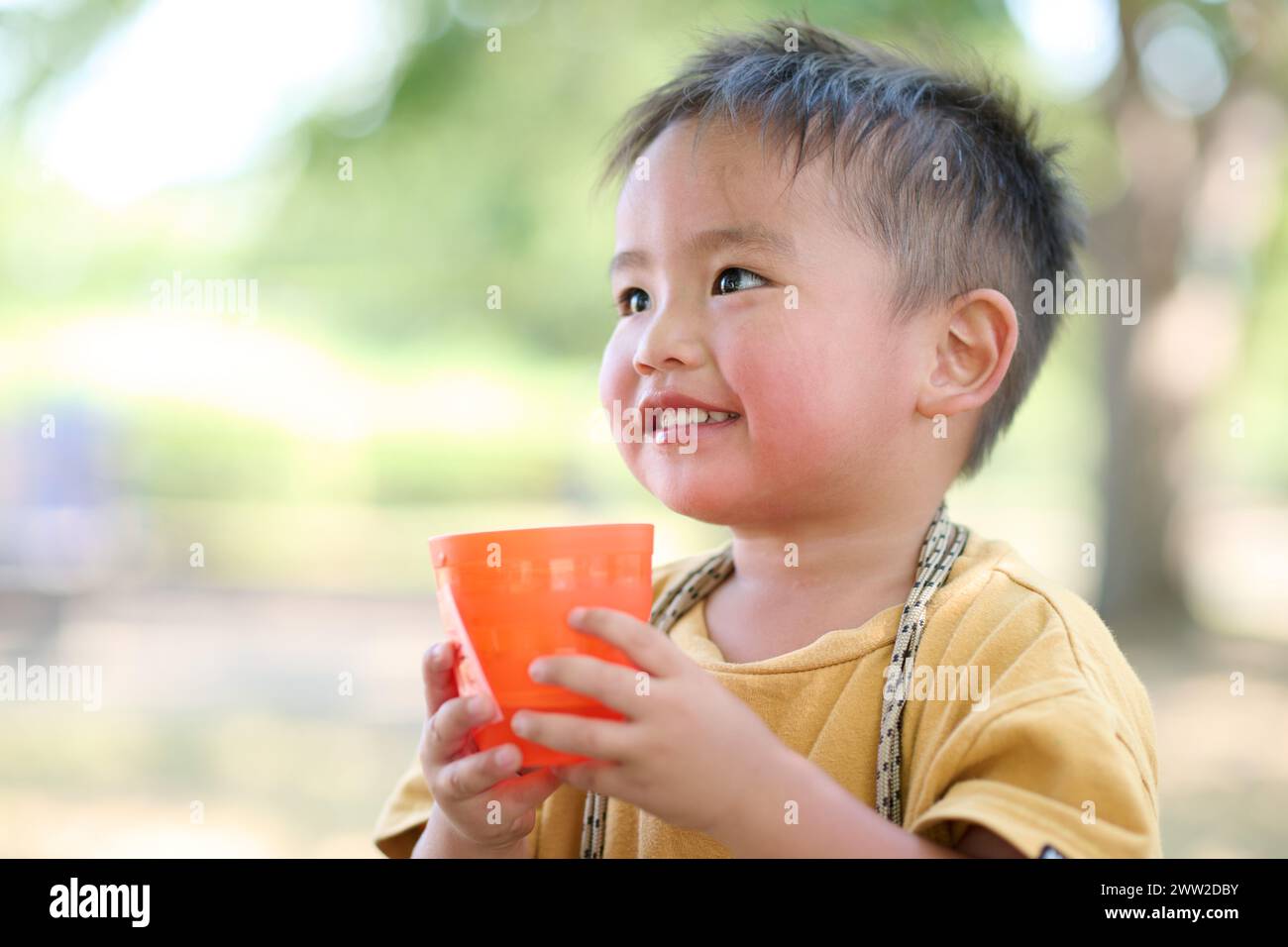 A young boy holding an orange cup Stock Photo - Alamy