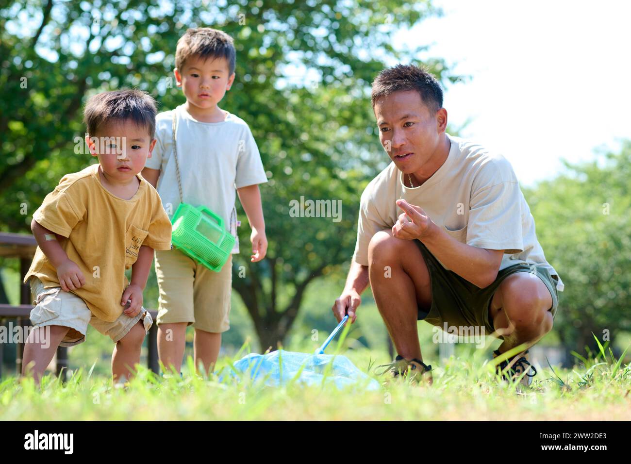 A man and kids playing in the grass Stock Photo - Alamy