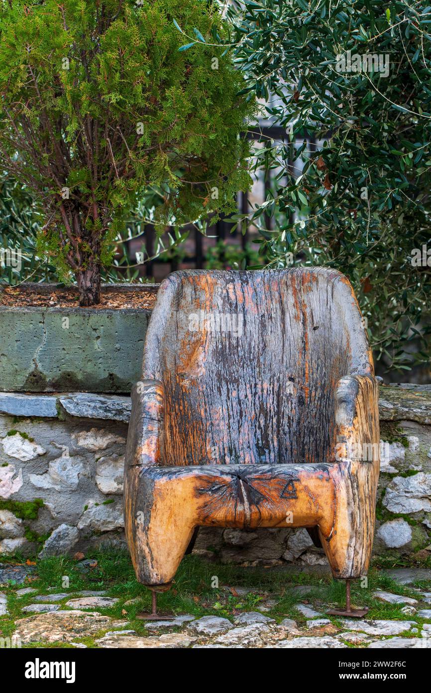 Old wooden dark and brown chair, with metal rusty leggings in the yard ...