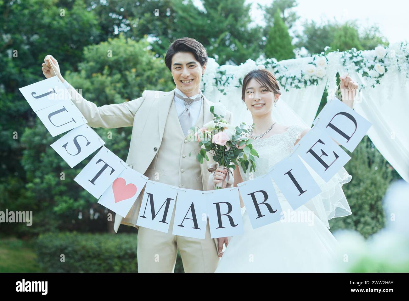 Just married couple holding wedding banner Stock Photo - Alamy