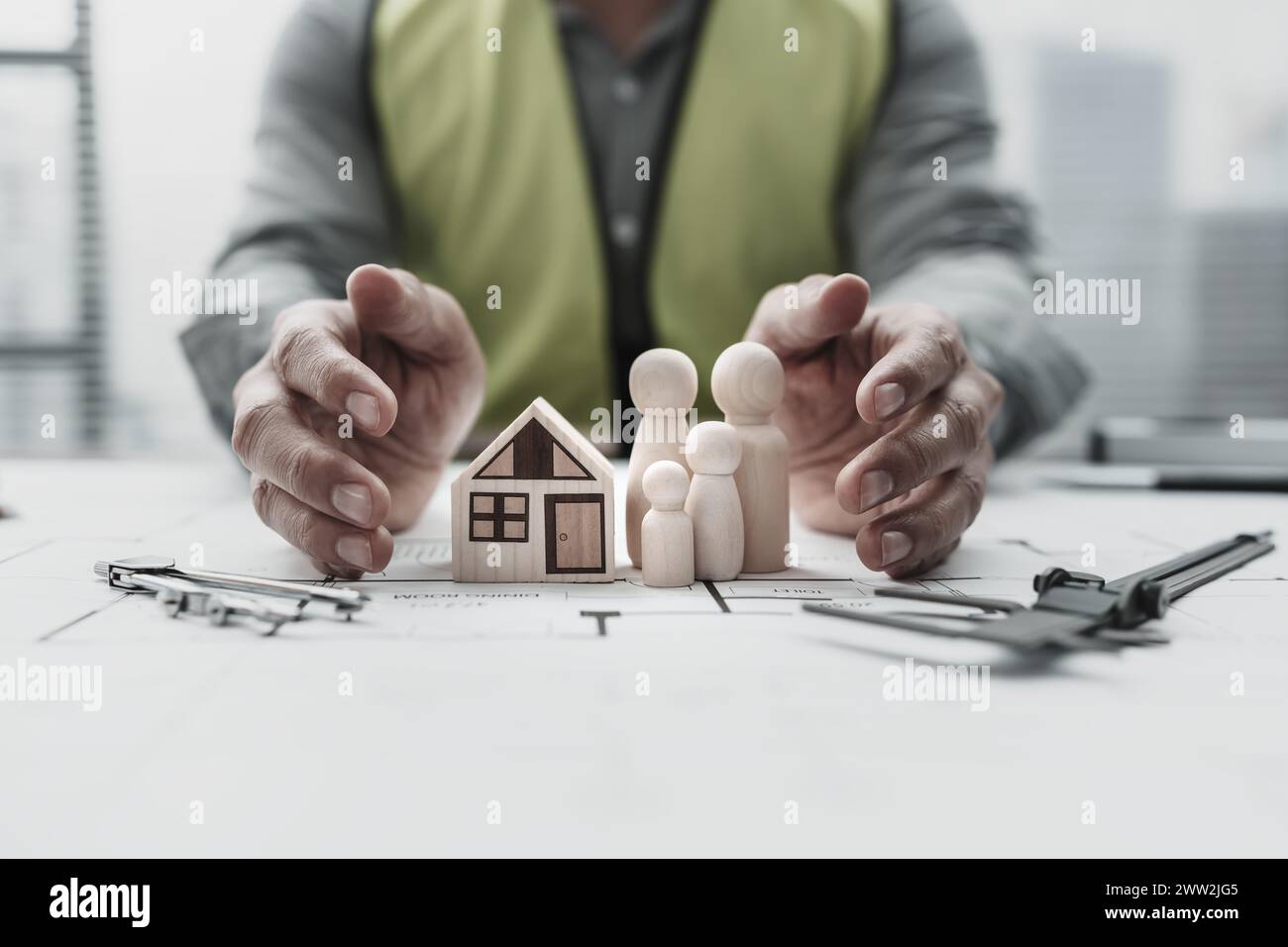 Architect, engineer hands protect house model and wood doll repersent ...