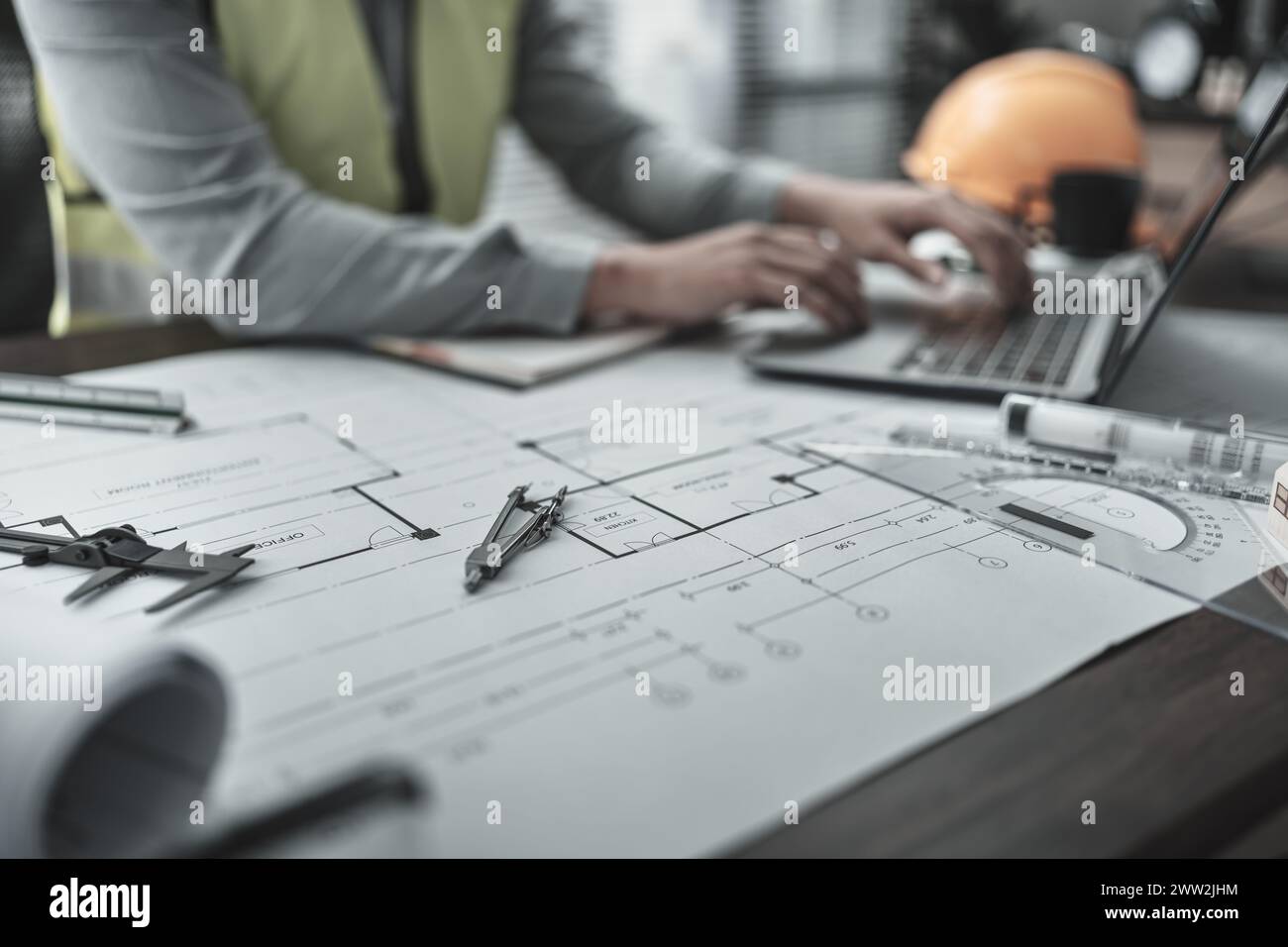 vernier caliper on blueprint in front of Architect working with laptop ...