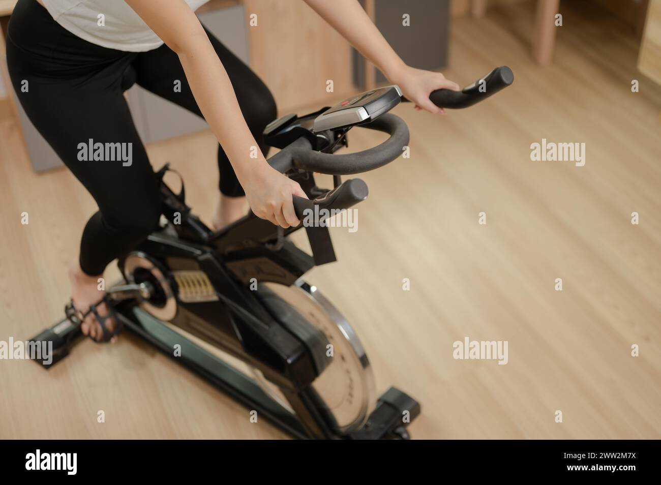 A cropped image of a woman in sportswear exercising on a fitness bike ...