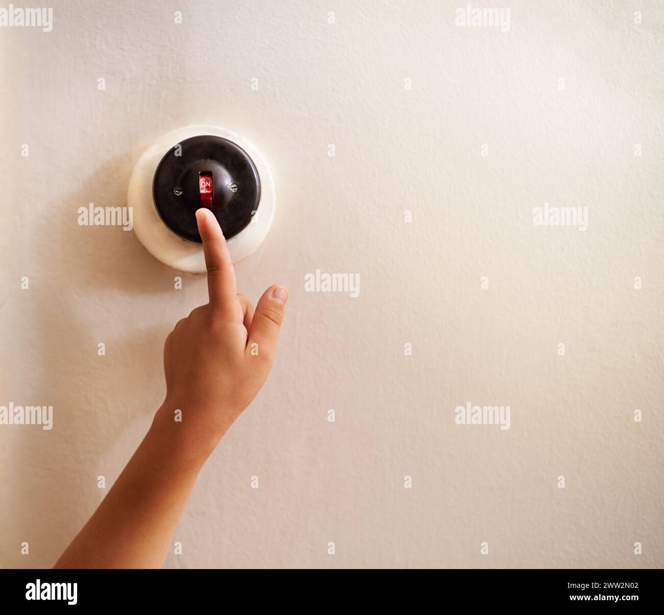 Hand, child and switch on wall for light, electricity and power in ...