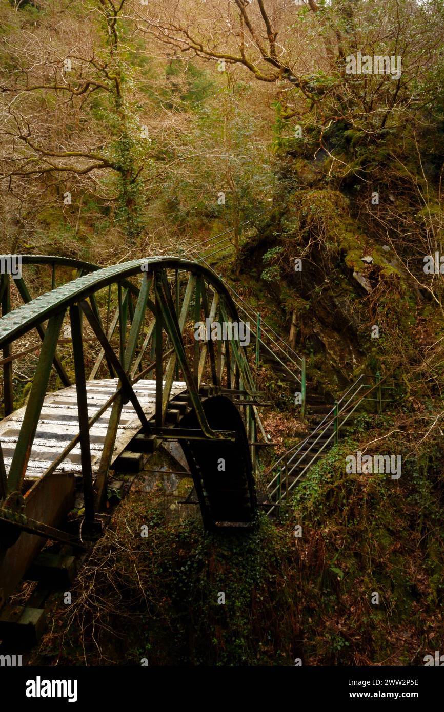Arched metal pedestrian bridge over the river Afon Mynach in Wales.UK ...