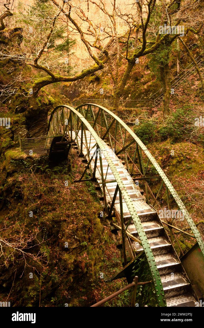 Arched metal pedestrian bridge over the river Afon Mynach in Wales.UK ...