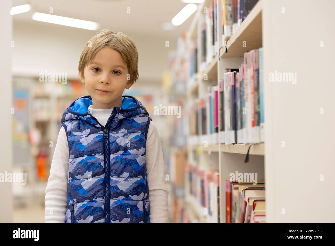 Smart child, school boy, educating himself in a library, borrowing ...