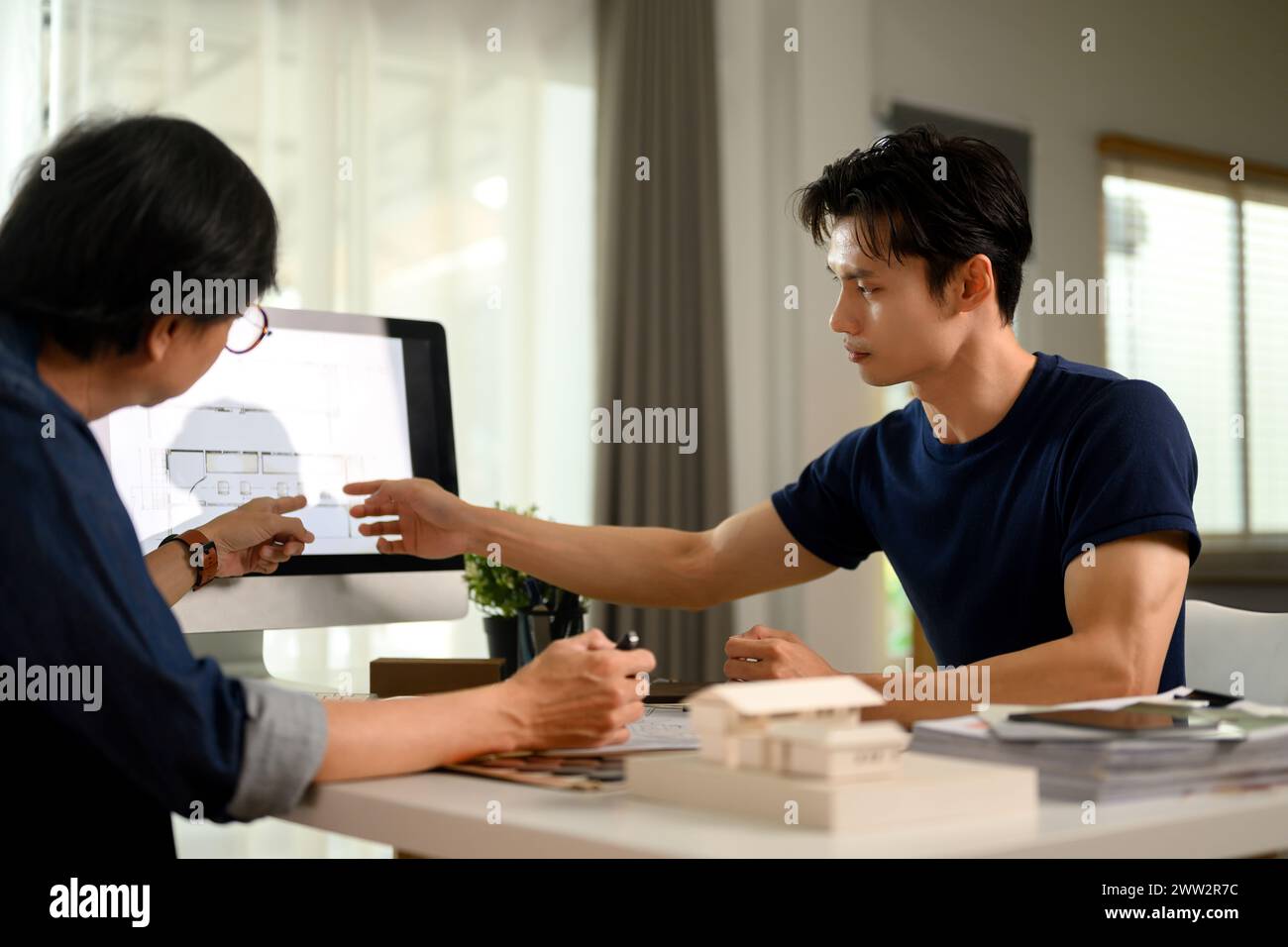 Millennial male client discussing building design project with professional architect in office ...