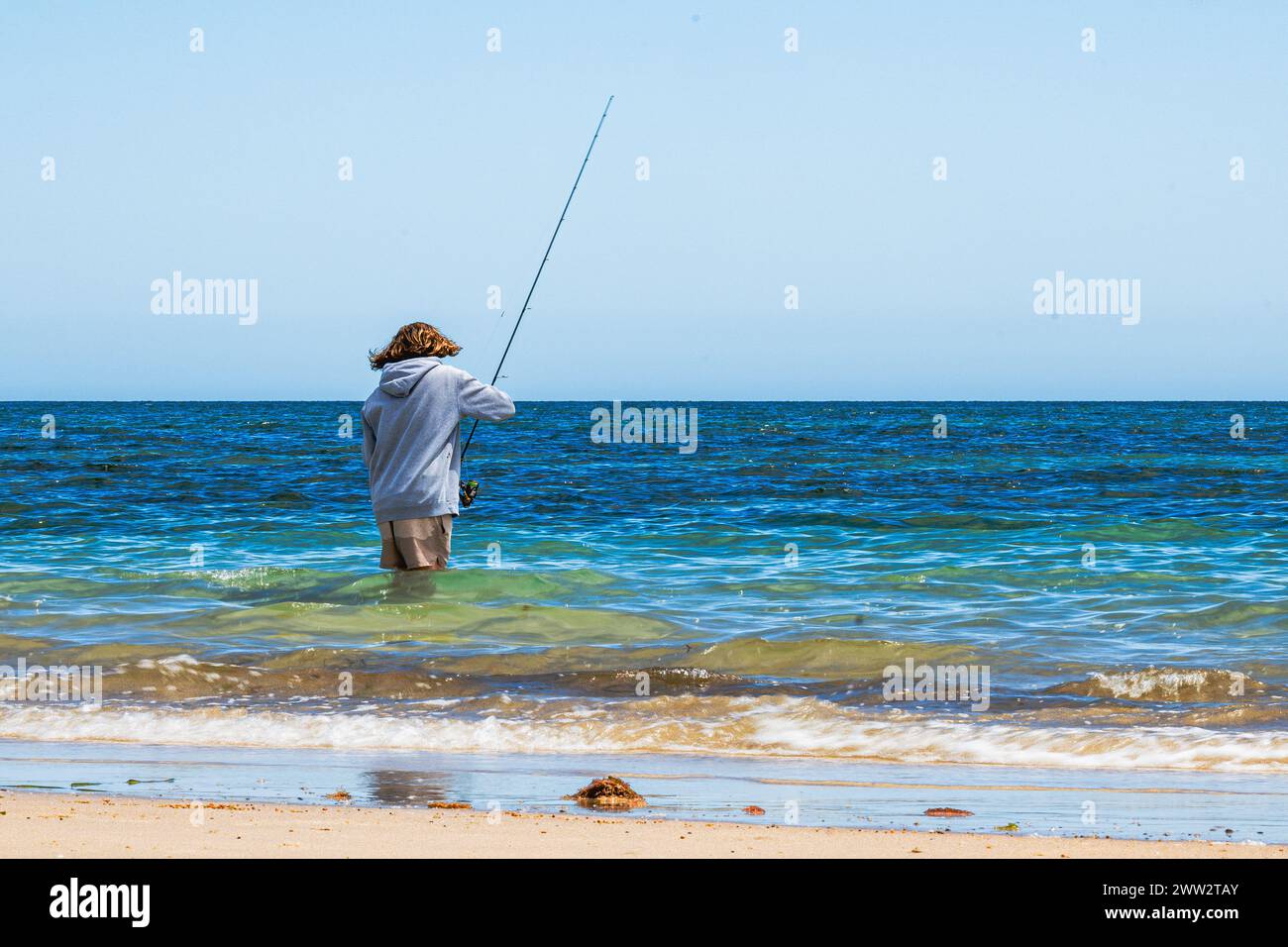 Against a backdrop of clear skies, an angler enjoys the serenity of ...