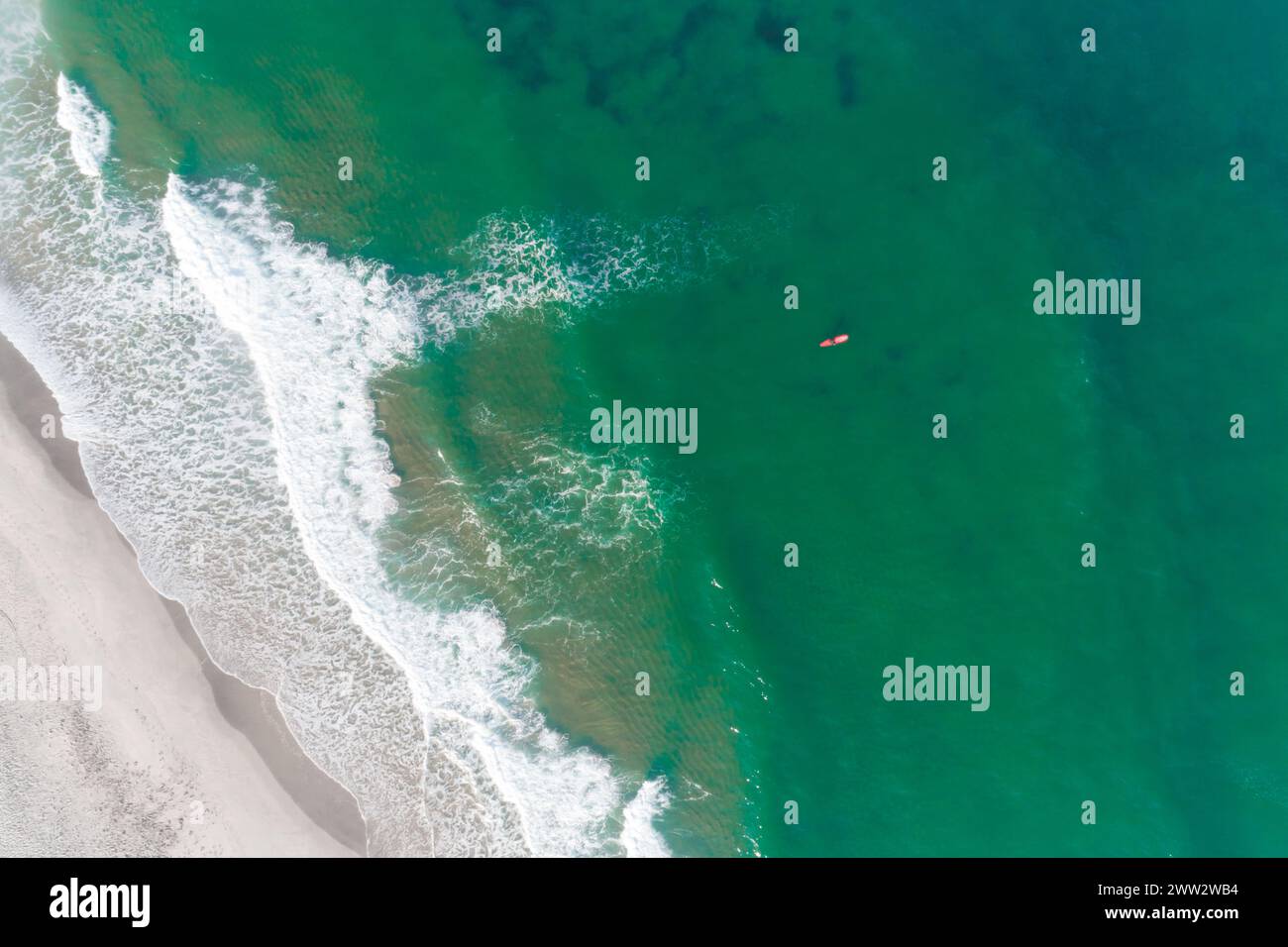 drone top view of a surfer with a red surfboard in the sea waiting for ...