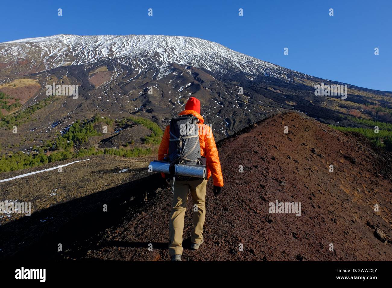 rear view hiker with backpack is walking along the ridge of extinct ...