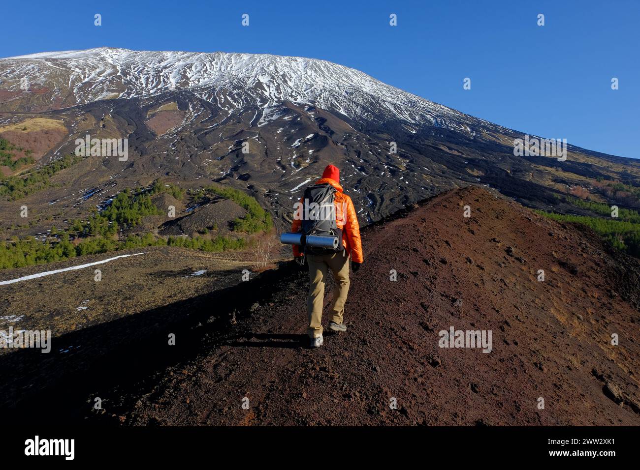 rear view hiker with backpack is walking along the ridge of extinct ...