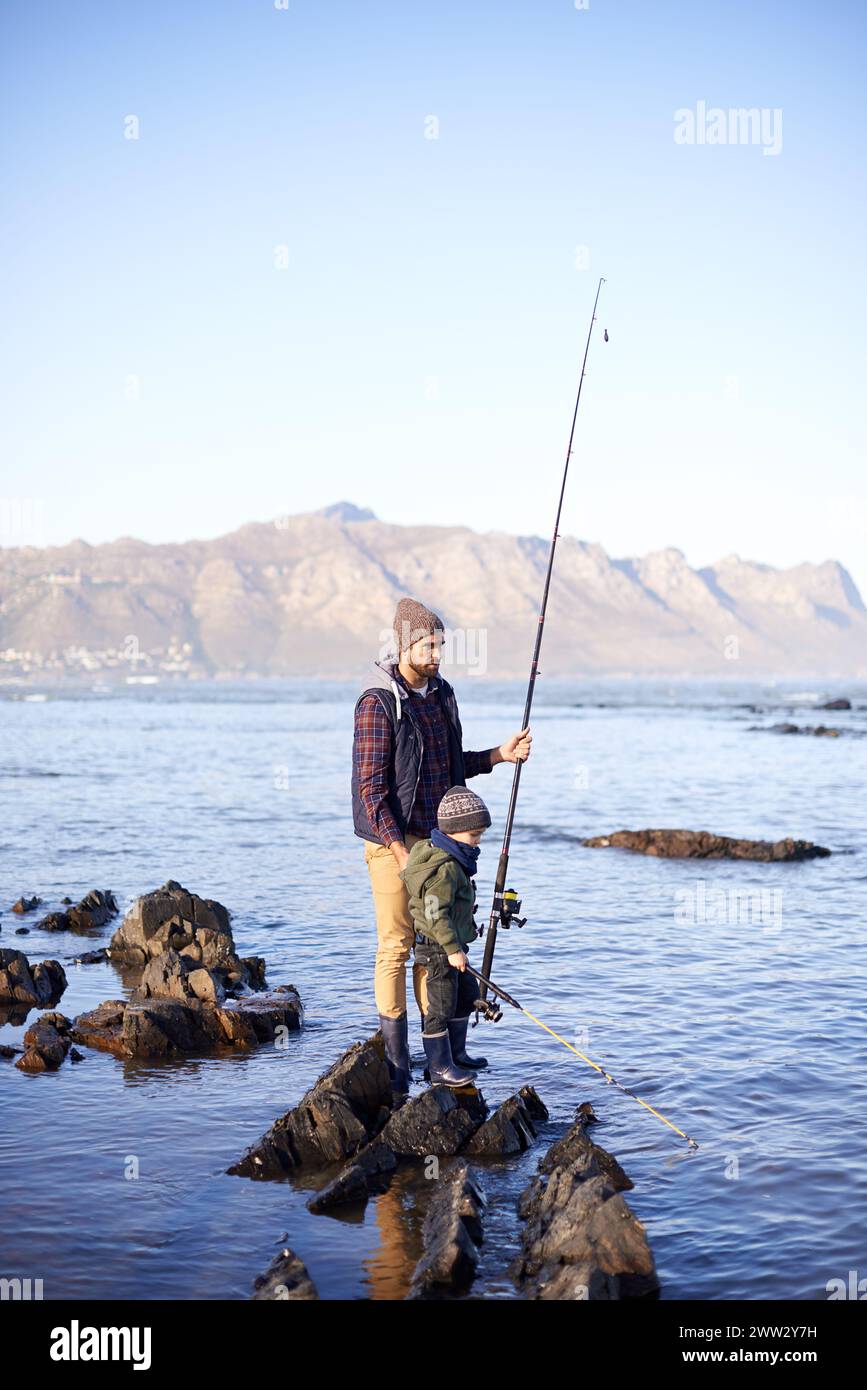 Father, fishing rod and young boy on rocks, teaching and bonding for ...