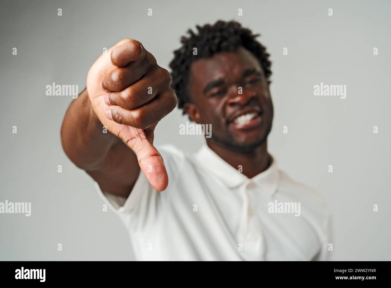 Young African Man Giving Thumbs Down Gesture Against a Neutral ...