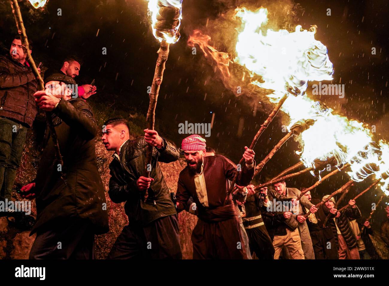 Akre, Iraq. 20th Mar, 2024. Iraqi Kurds carry fire torches as they ...