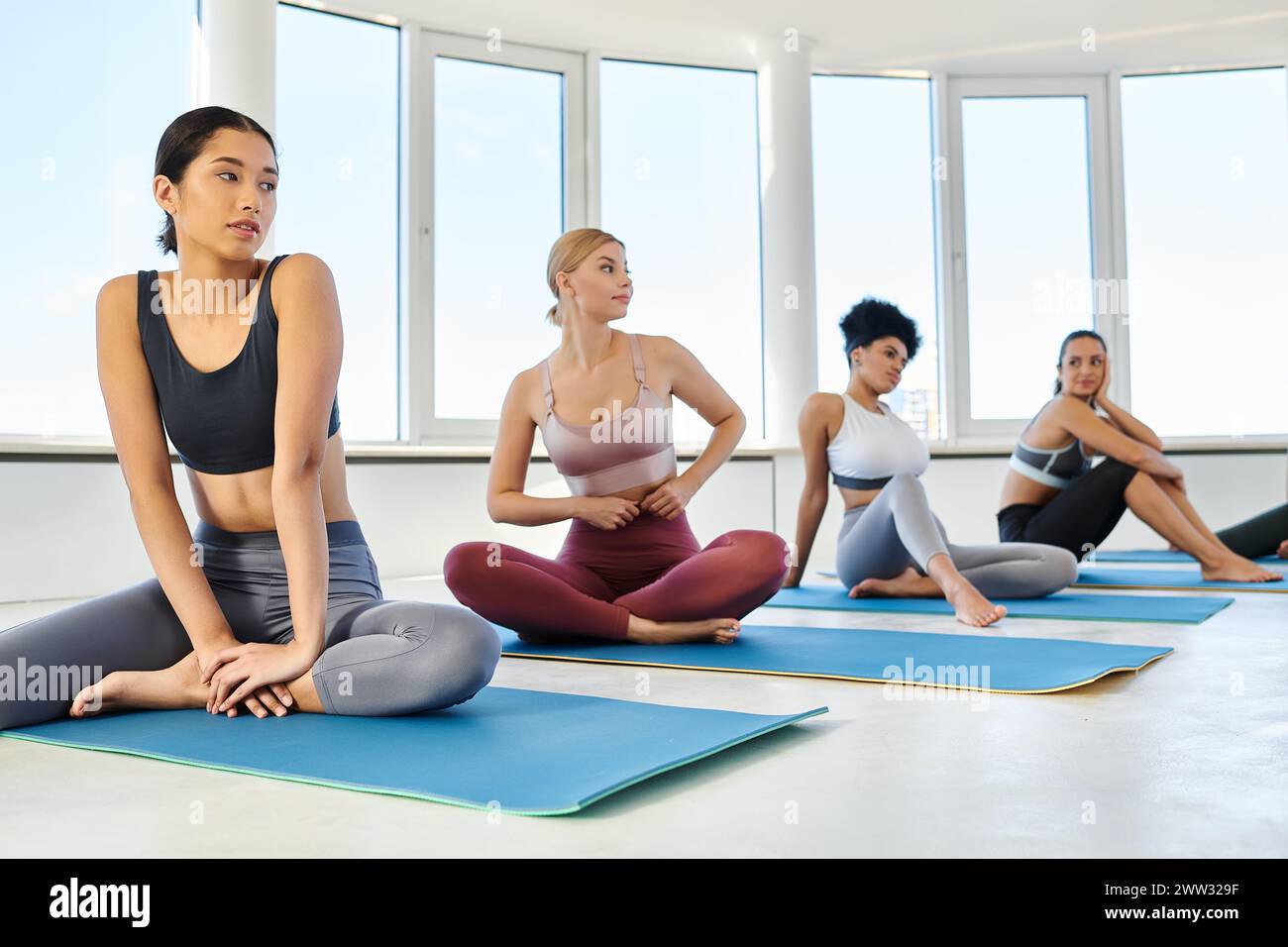 young asian woman in sportswear sitting on mat next to multicultural ...