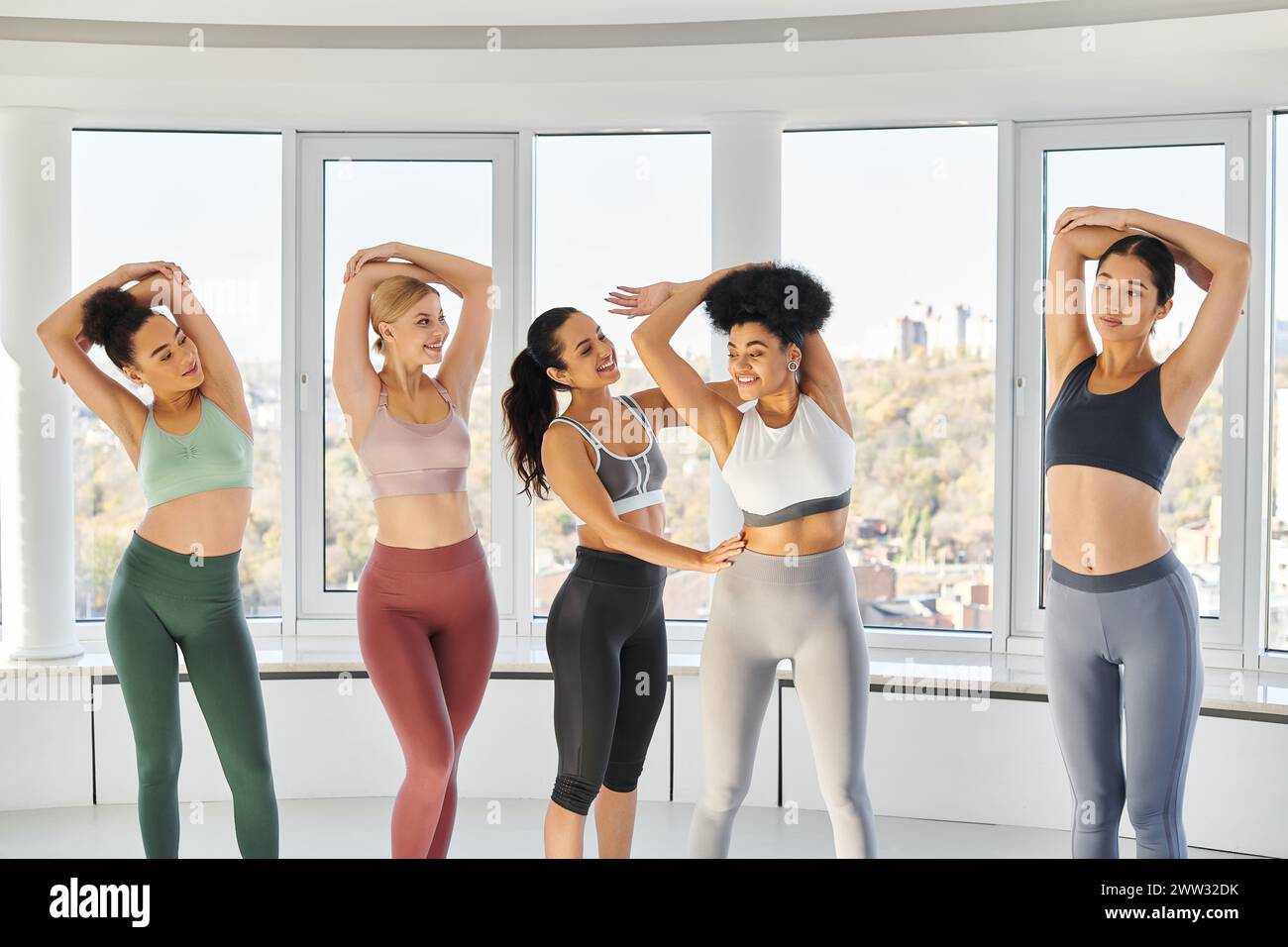 happy female pilates trainer helping african american woman with her ...