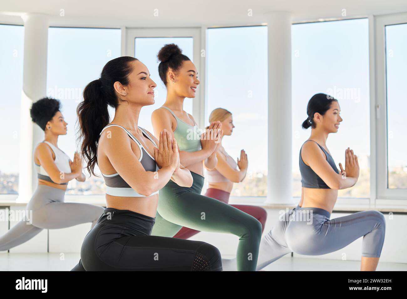 group of happy multicultural women doing lunges with praying hands ...