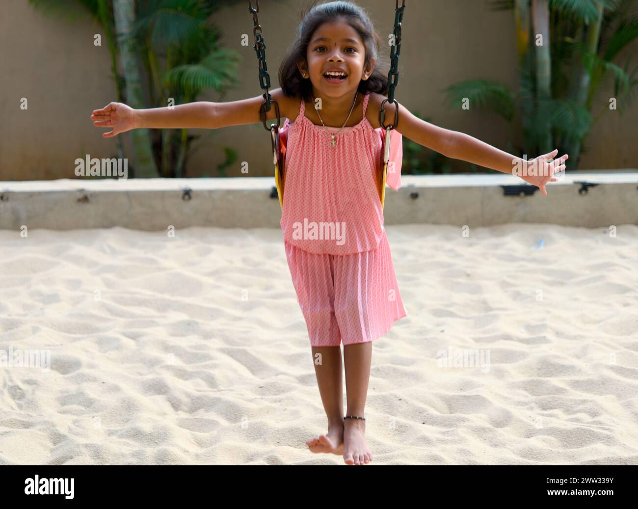 A carefree young girl laughs with delight as she pumps her legs ...