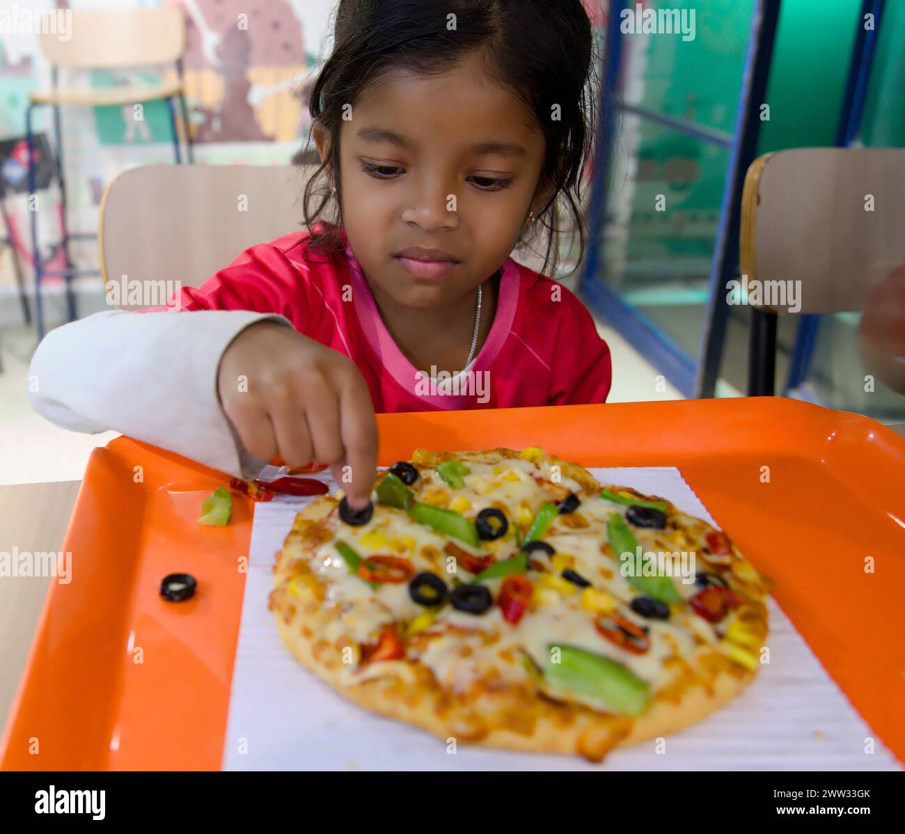 A close-up portrait of a young girl savoring a delicious slice of pizza ...
