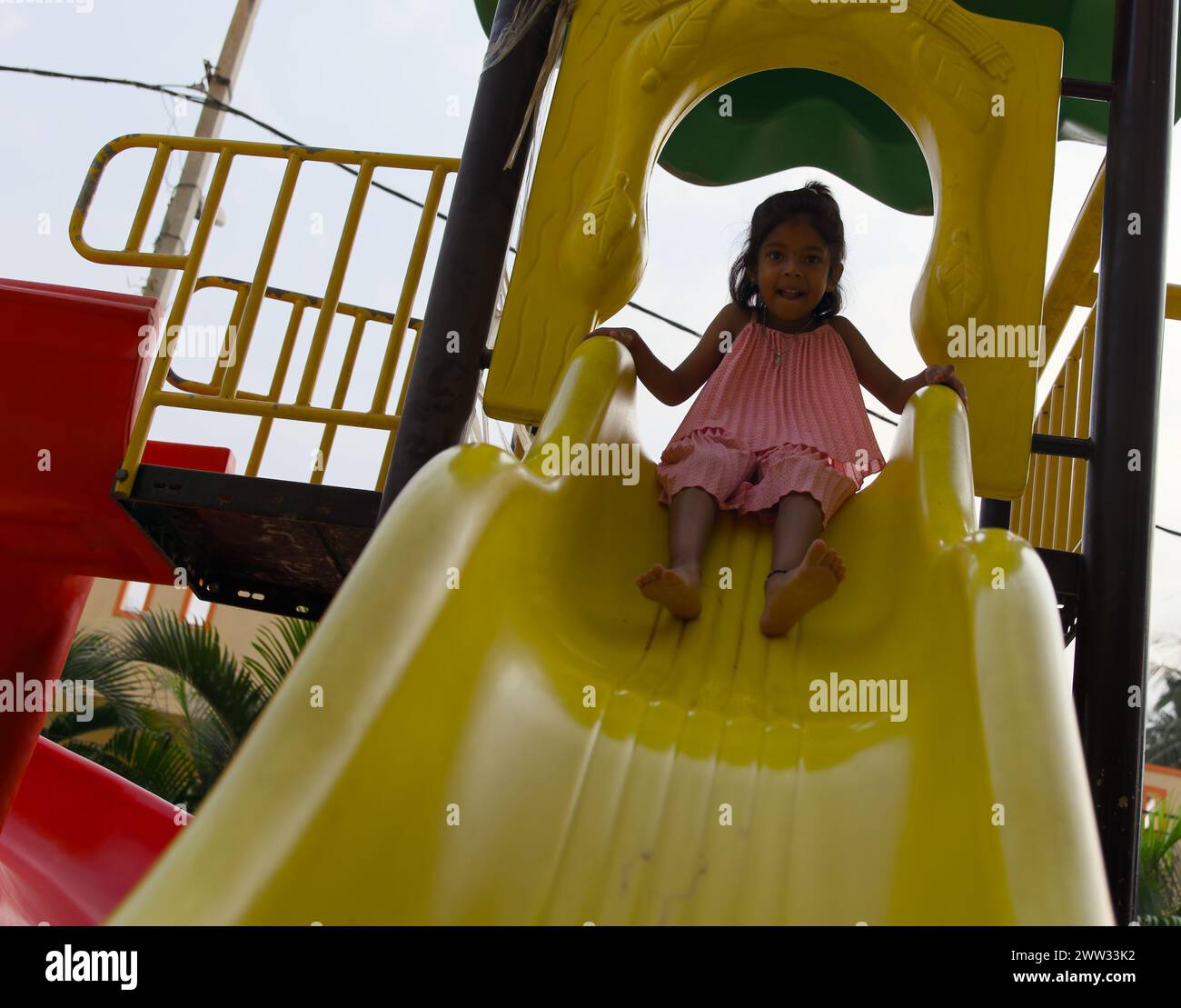 A carefree young girl laughs with delight as she zooms down a colorful ...