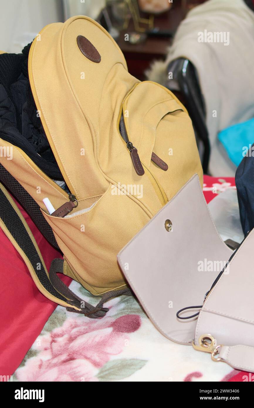 A yellow backpack and a gray bag are messily placed on a bed with ...