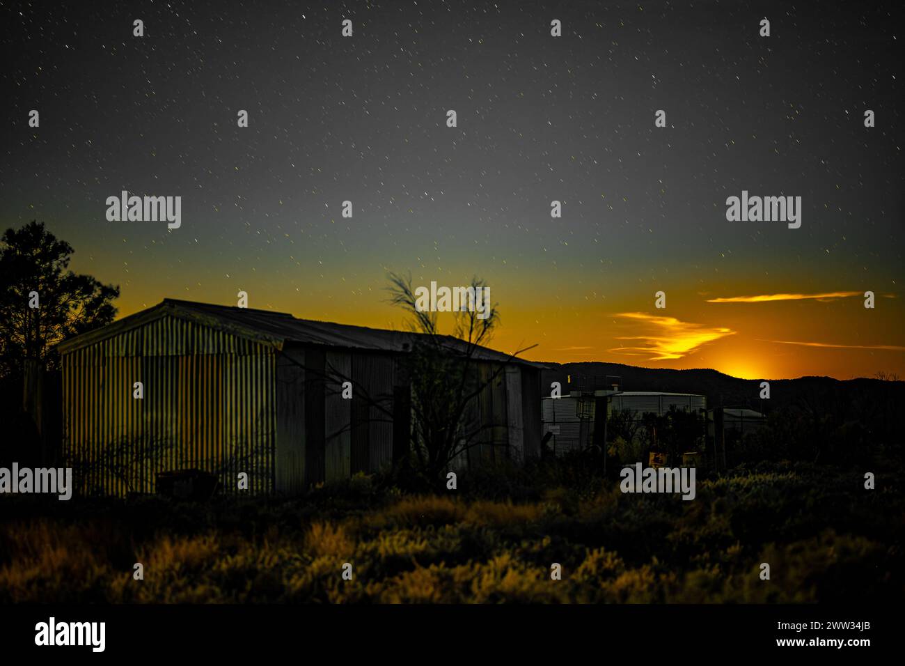 A rural shed under a starlit sky, with the last glow of sunset on the ...