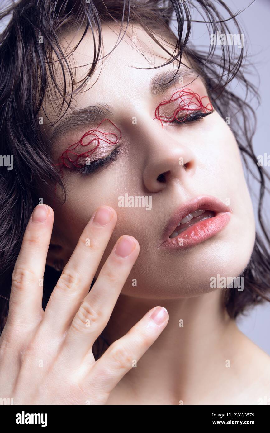 Close-up portrait of young beautiful girl with wet hair, red string ...