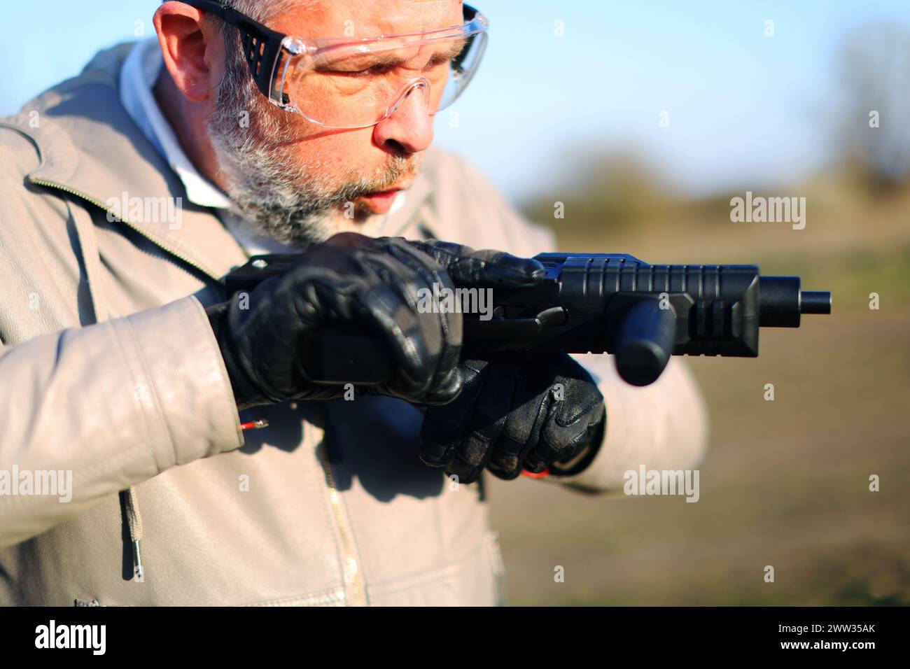 Man with gray jacket shooting black rifle on range clean the gun Stock ...