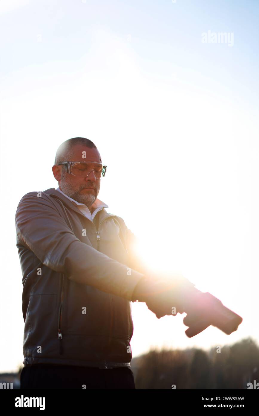 Man with gray jacket shooting black rifle on an openair shooting range ...