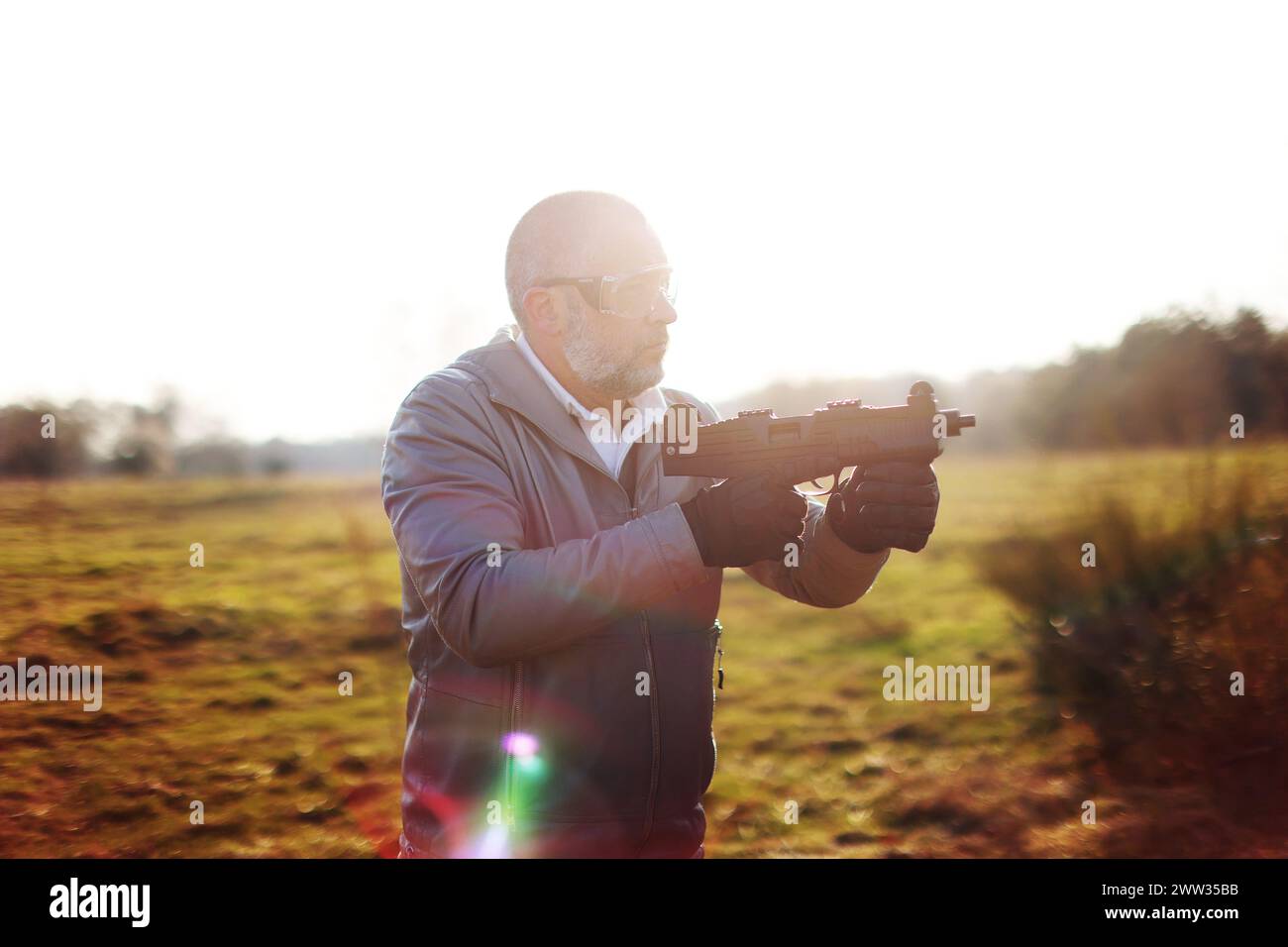 Man with gray jacket shooting black rifle on an openair shooting range ...