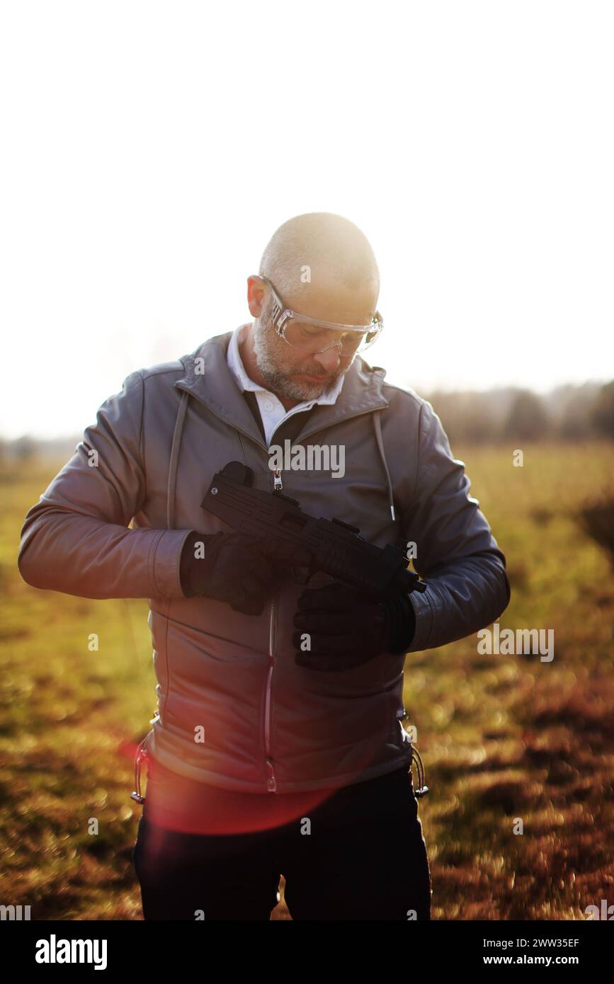 Man with gray jacket shooting black rifle on an openair shooting range ...