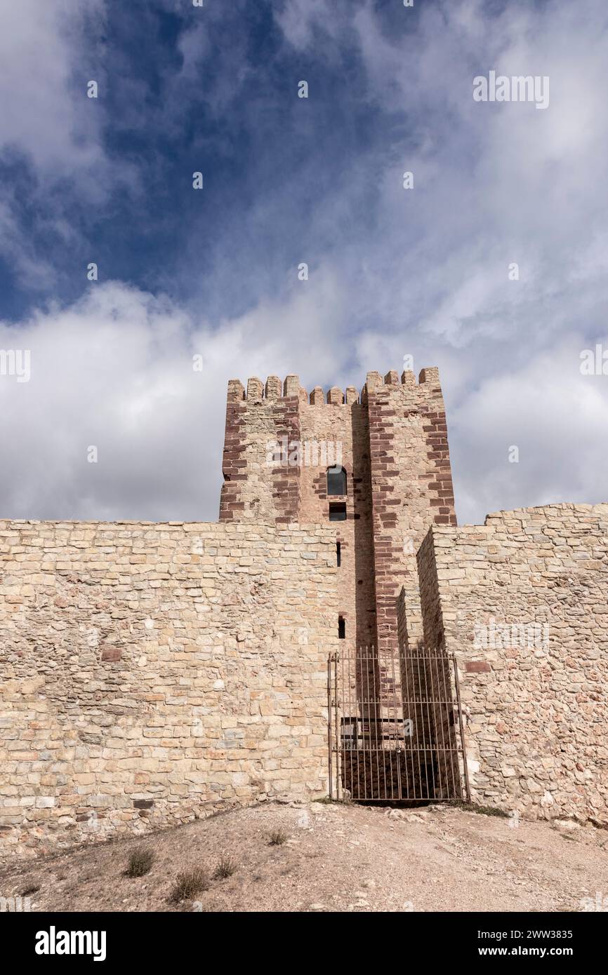 ancient stone fortress with a gated entrance stands under a cloudy sky, exuding historical and ...