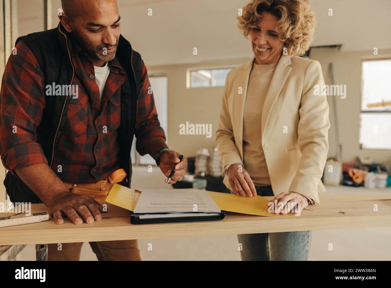 Happy contractor and homeowner sign documents indoors. They are ready ...