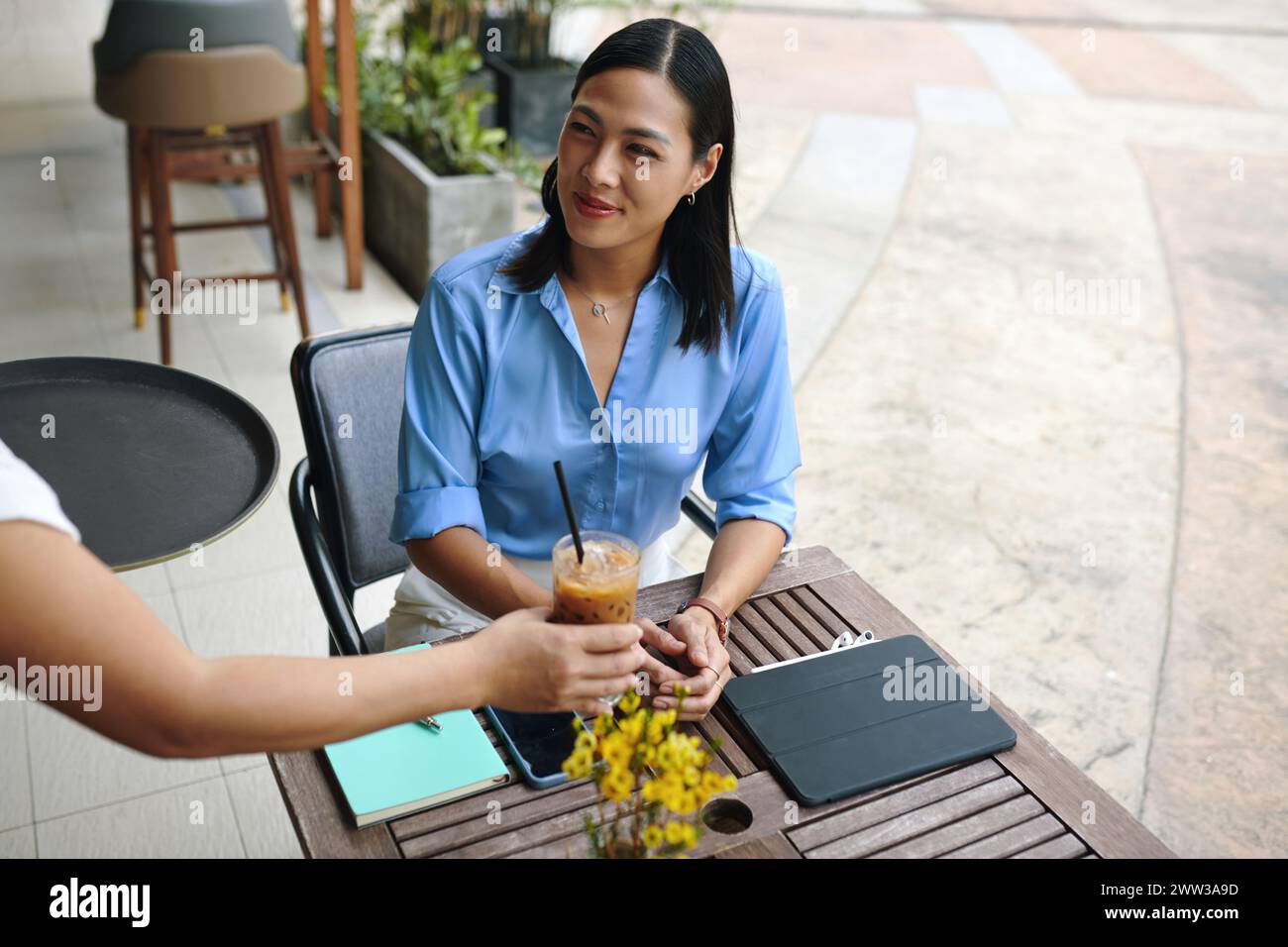 Waiter bringing iced coffee to happy businesswoman Stock Photo - Alamy