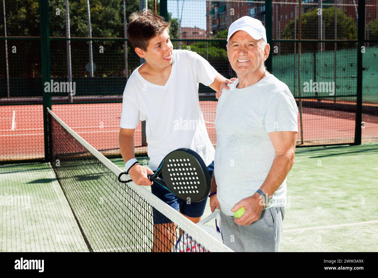Padel players of different generations talking on court playing paddle ...