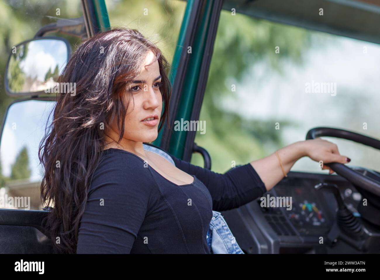 Hispanic voluptouos woman at the helm of a truck, hands on the steering ...
