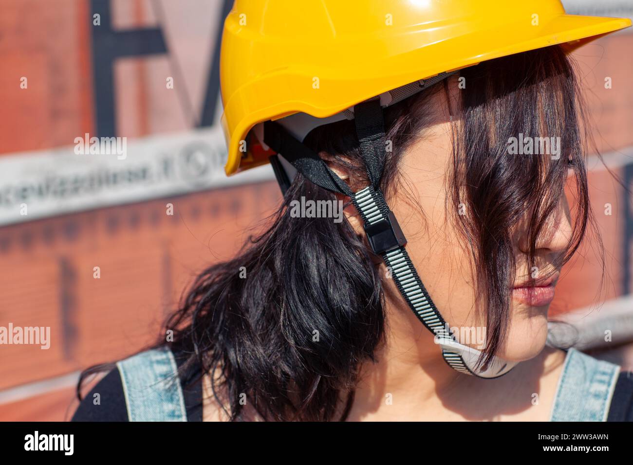 Close-up of a woman wearing a yellow safety helmet in construction site ...