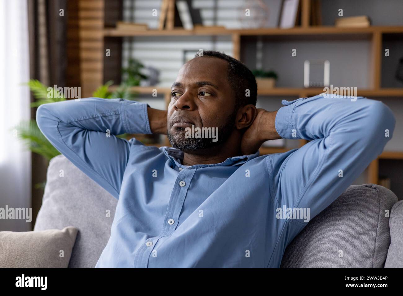 Portrait of a thoughtful African American man lounging on a couch ...