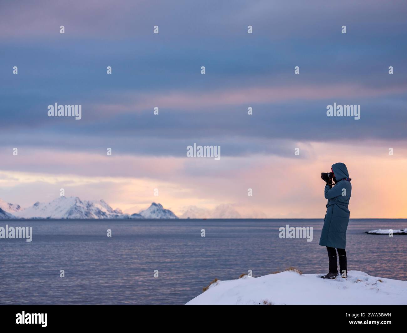 Photographer on a snow-covered hill, mountains and sea in the ...