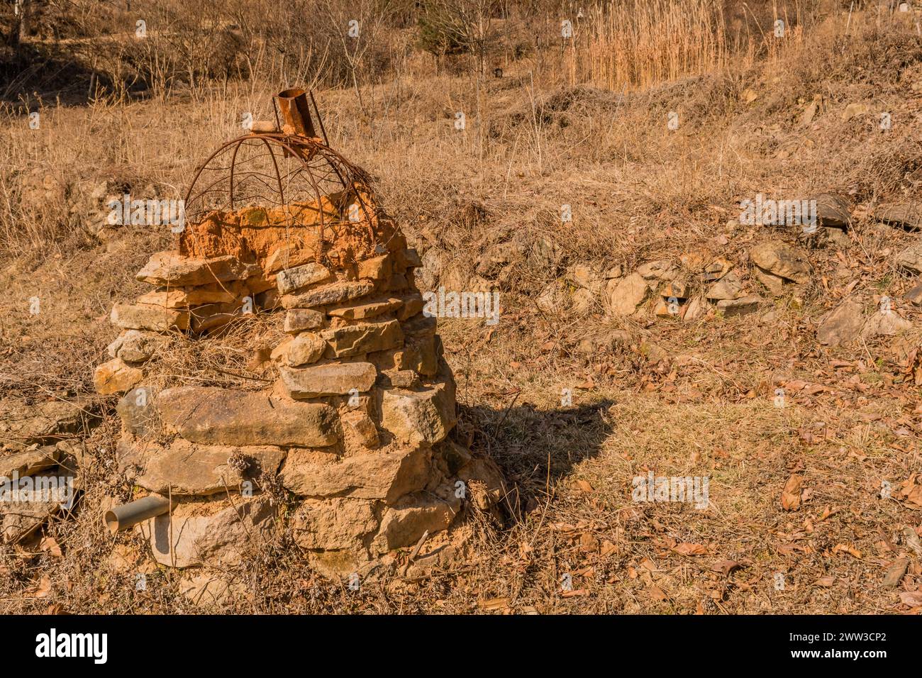 Stone structure with rusted wire frame and pipe sticking out of bottom ...