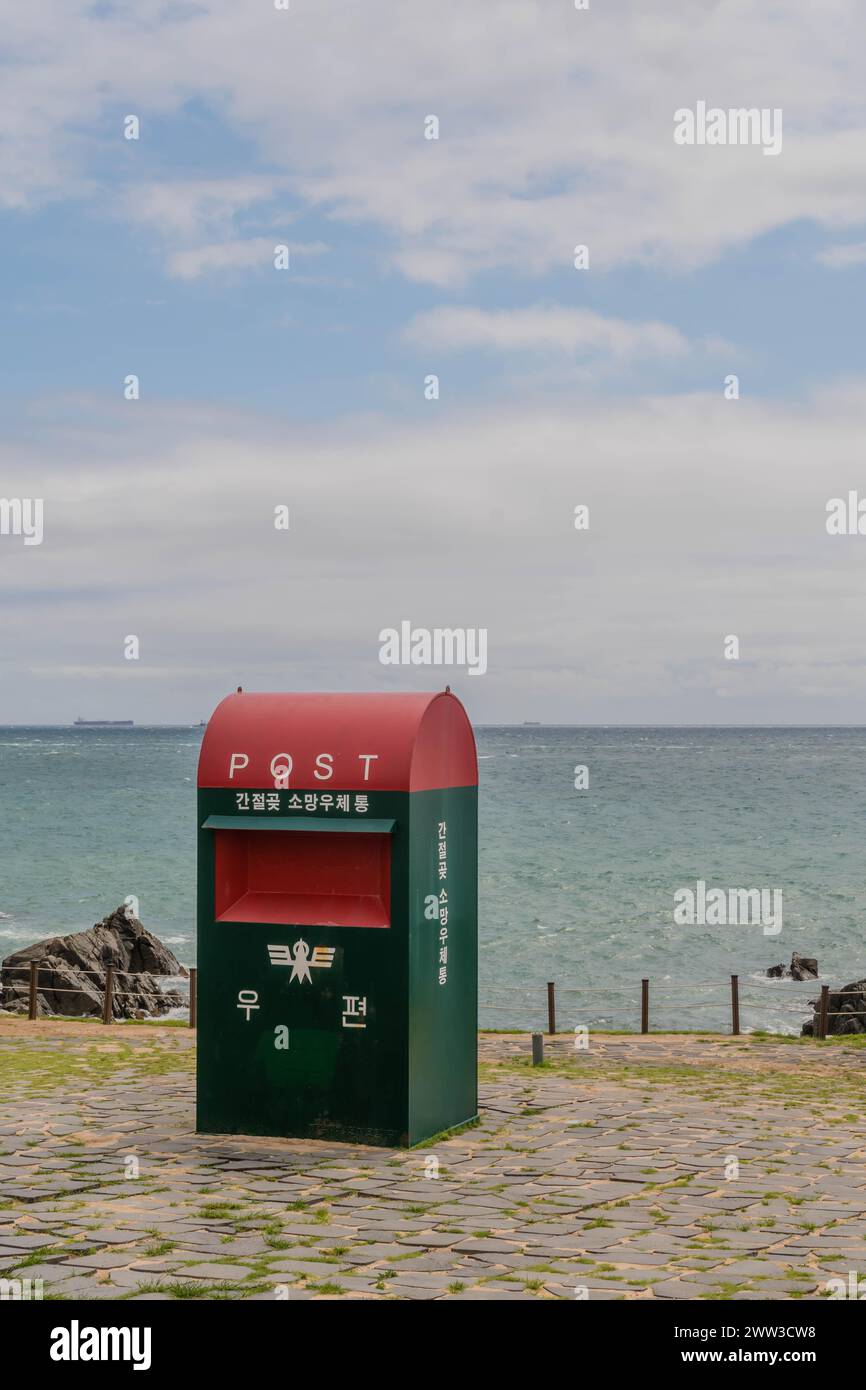 Red and green post box by the ocean with a cloudy sky above, in Ulsan ...